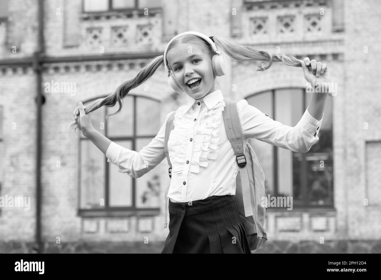 Happy school girl in uniform having fun listening to music in ...