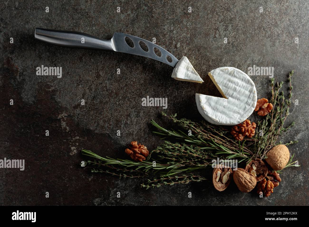 Brie cheese with walnuts, thyme, and rosemary on an old stone ...
