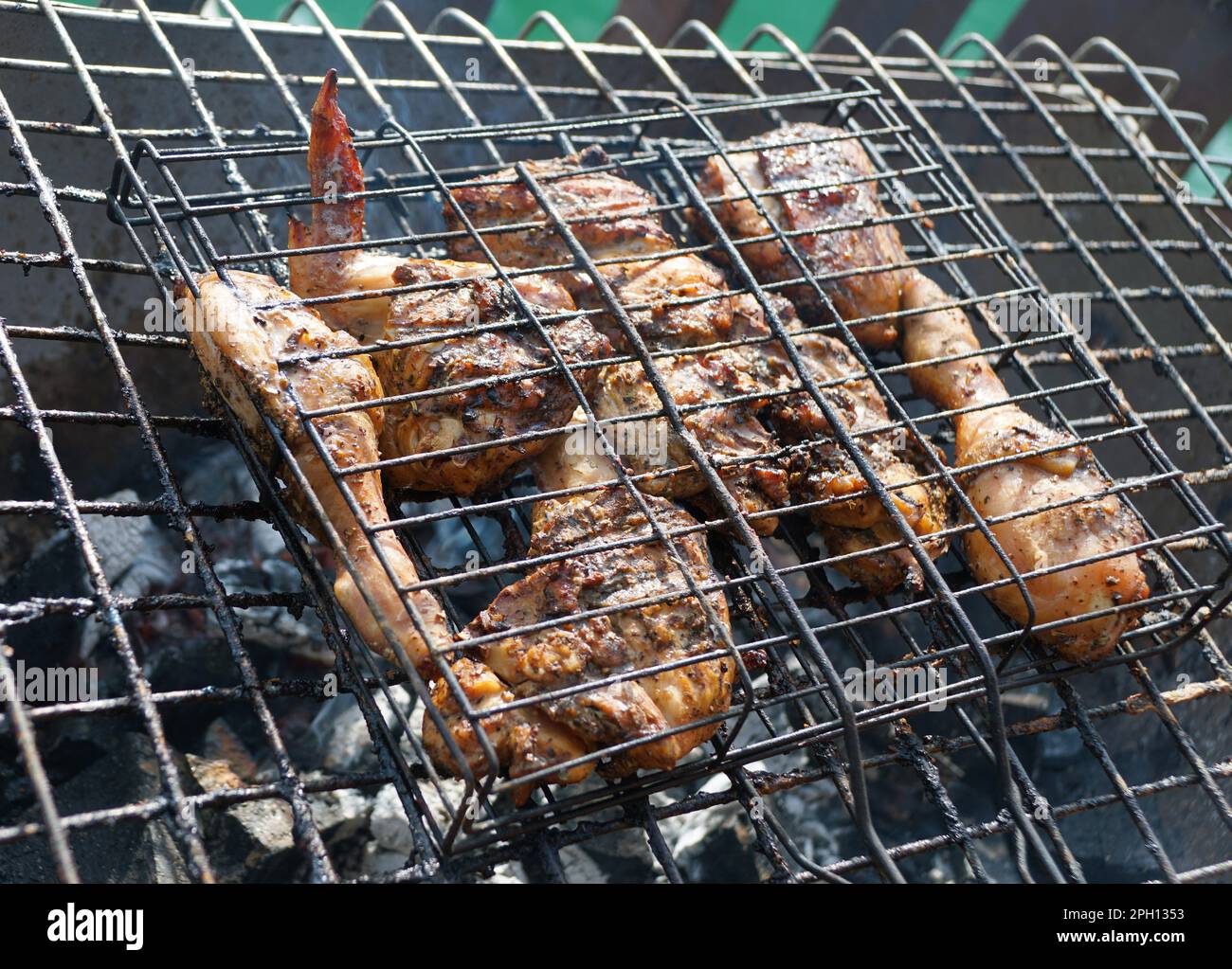 Close up of the grilled chicken inside of a stainless steel basket ...