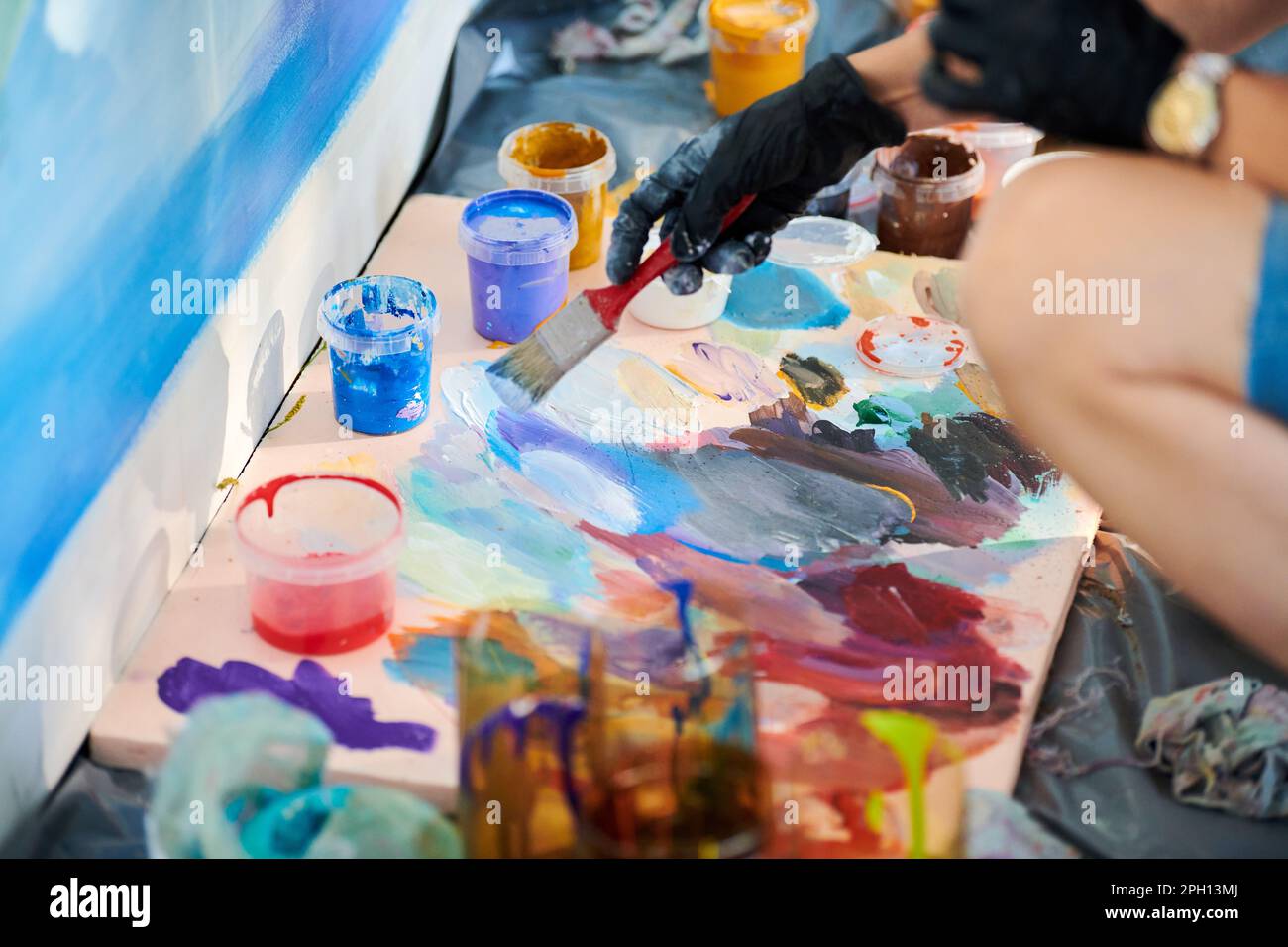 Artist hand in black gloves holds paint brush and choose color from ...