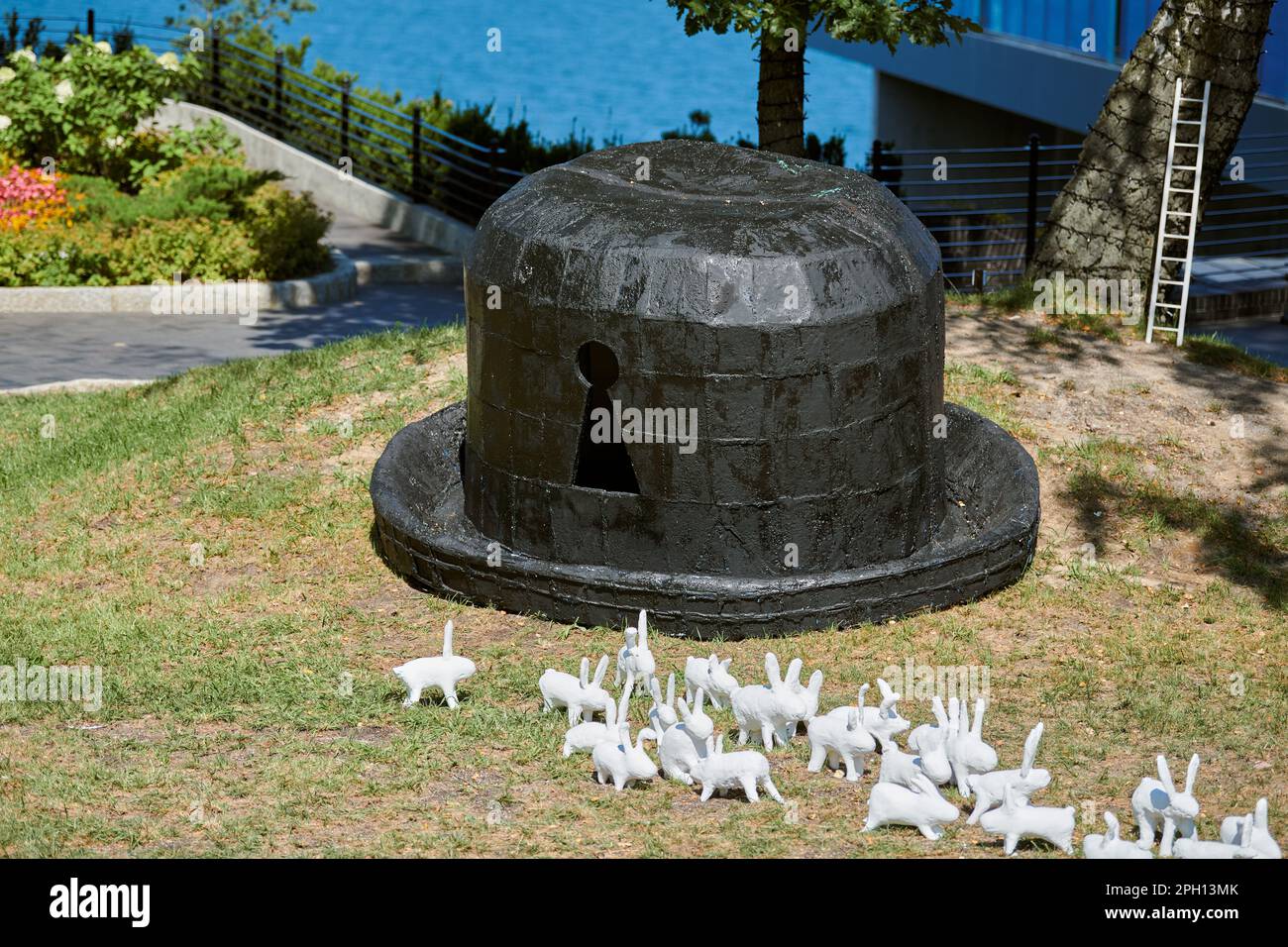 Art installation big black hat with keyhole on green grass and white ...