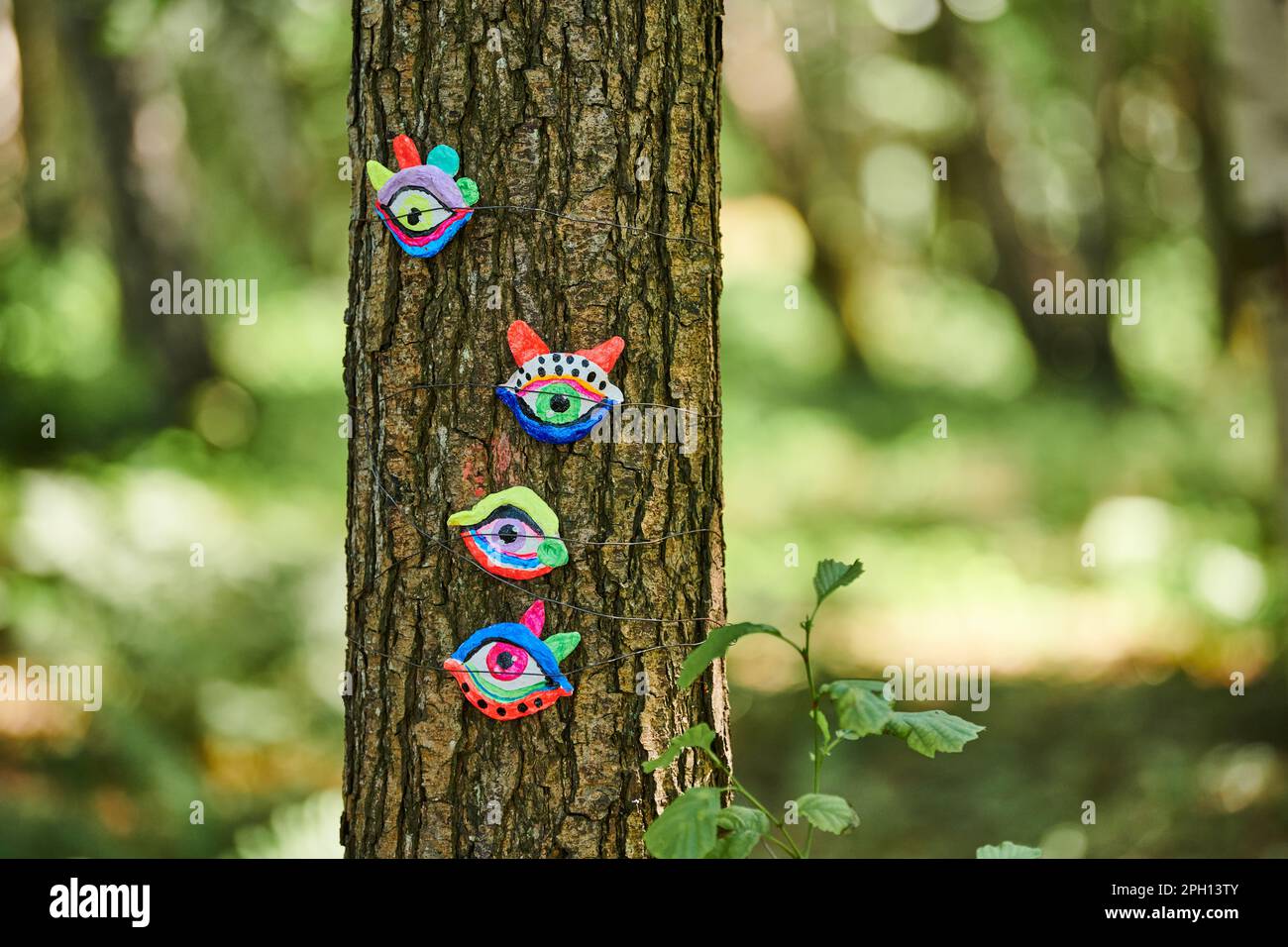 Art object of human eyes on tree trunk in green forest background ...