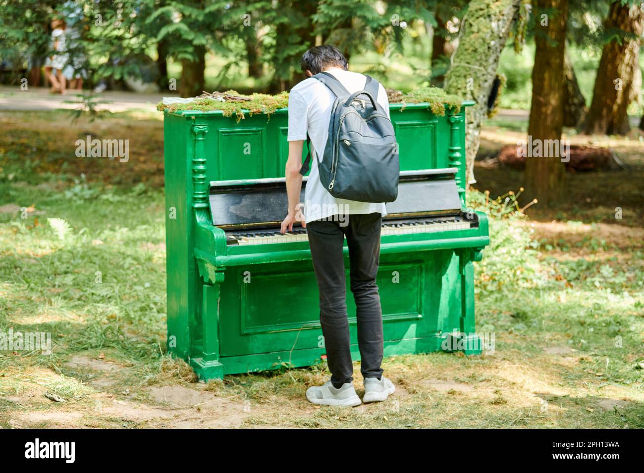 Young guy teenager plays classic music on piano, interactive outdoor ...