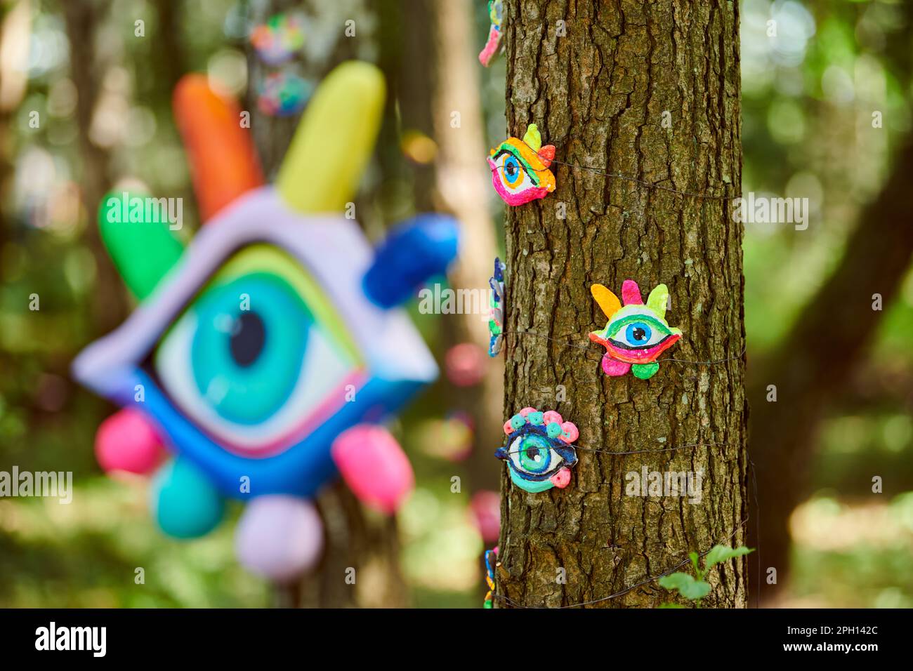 Art object of human eyes on tree trunk in green forest background ...