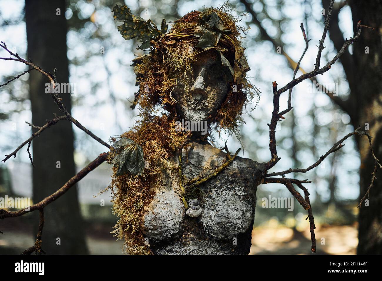 Creepy witch statue art object on forest background made of mud plaster ...