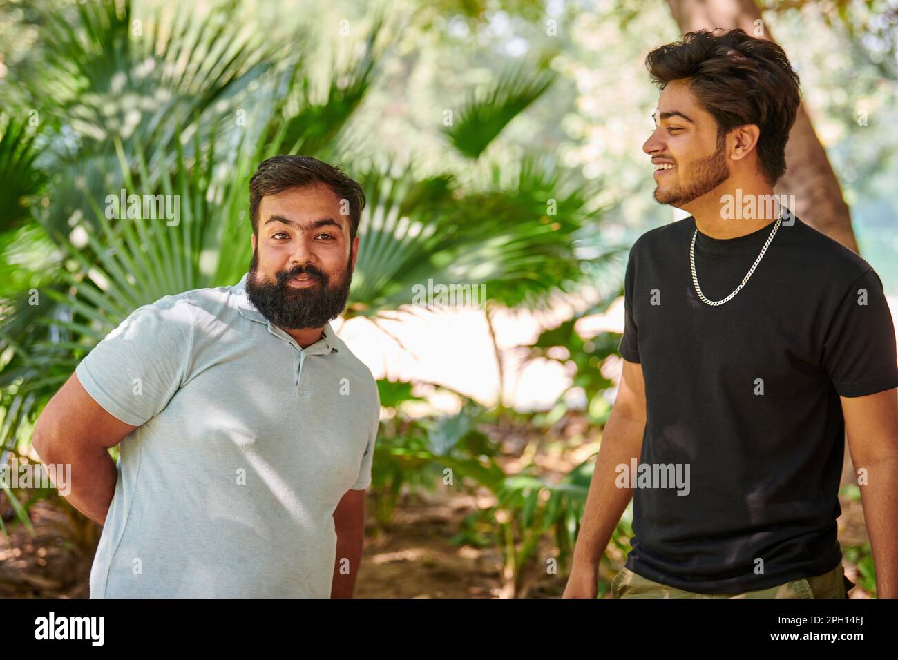 Two funny indian men laughing and speak Hindi in public park green palm ...