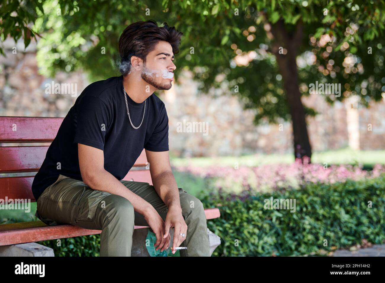 Attractive indian man smoker exhales cigarette smoke portrait in black ...