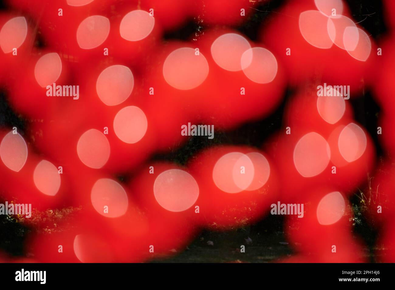 Blurred defocused red balls suspended on wire, outdoor art object ...