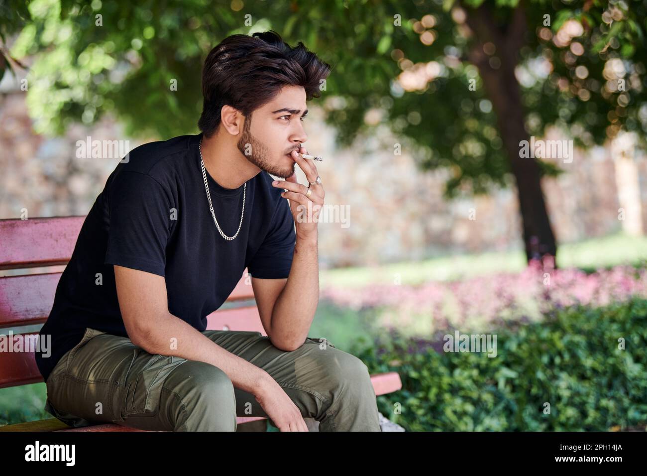 Young indian man smoker portrait in black t shirt and silver neck chain ...