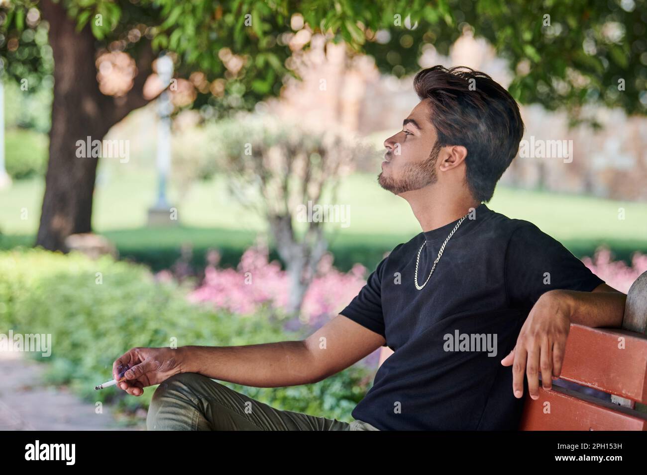 Attractive indian man smoker exhales cigarette smoke portrait in black ...