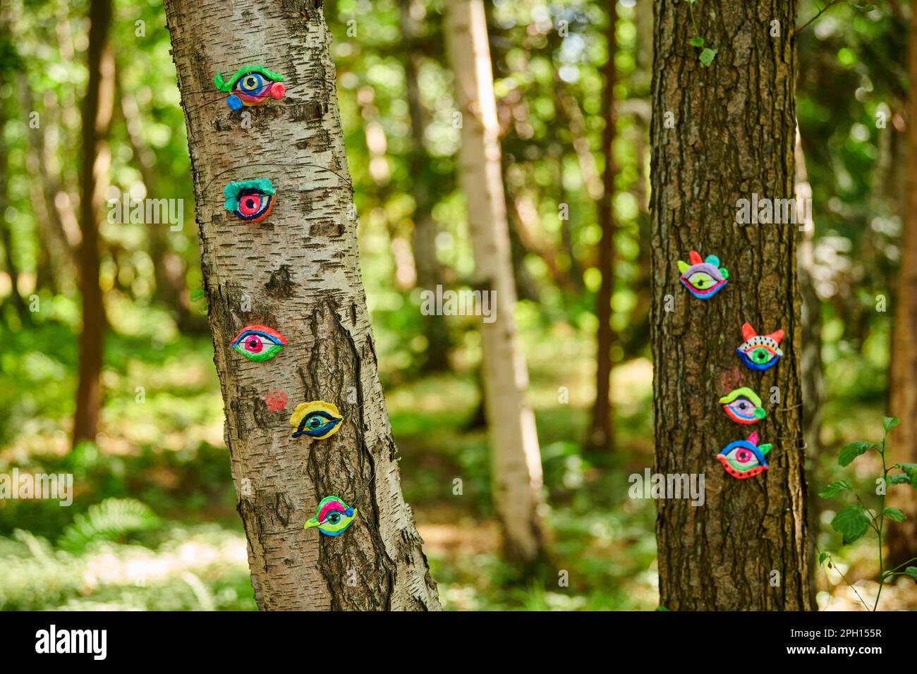 Art object of human eyes on tree trunk in green forest background ...