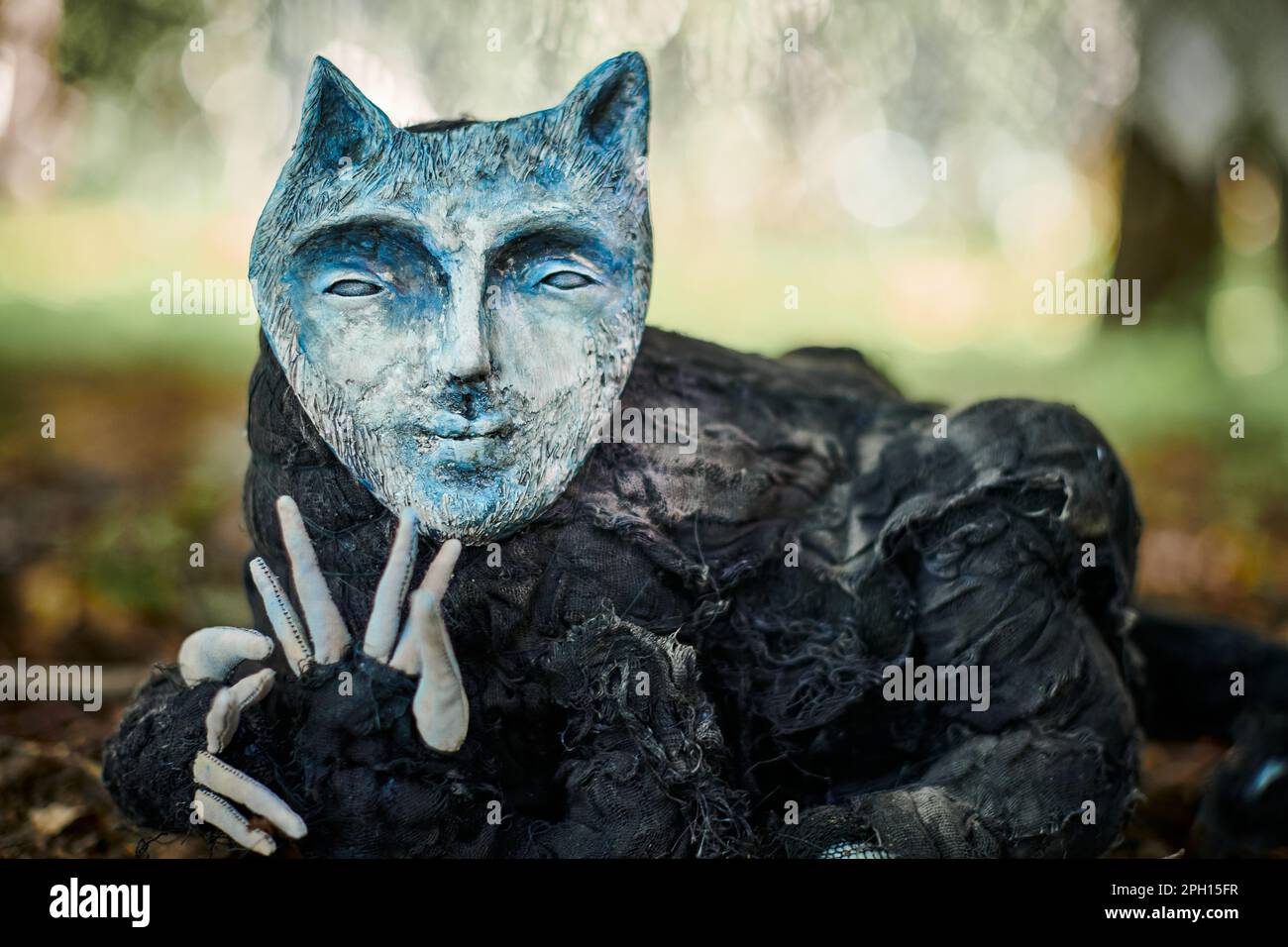 Black cat in human face mask art object at outdoor art exhibition in ...