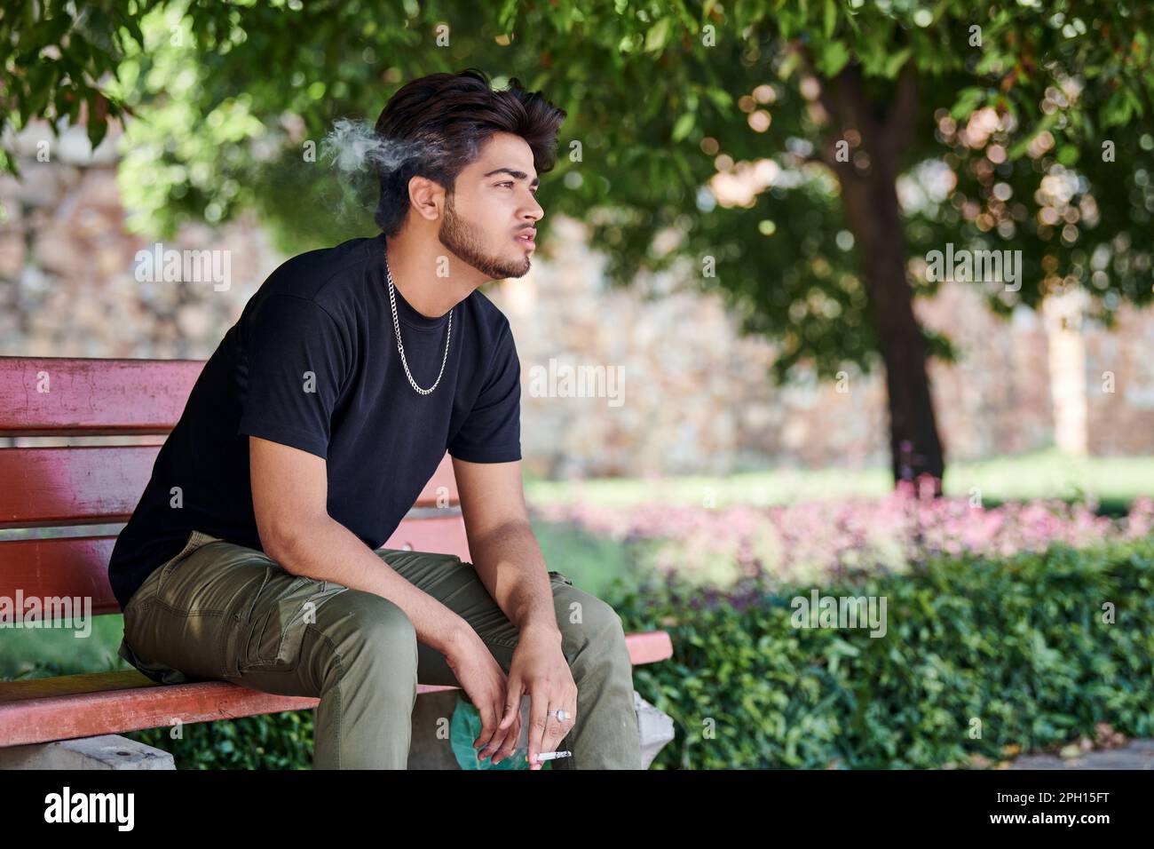 Attractive indian man smoker exhales cigarette smoke portrait in black ...