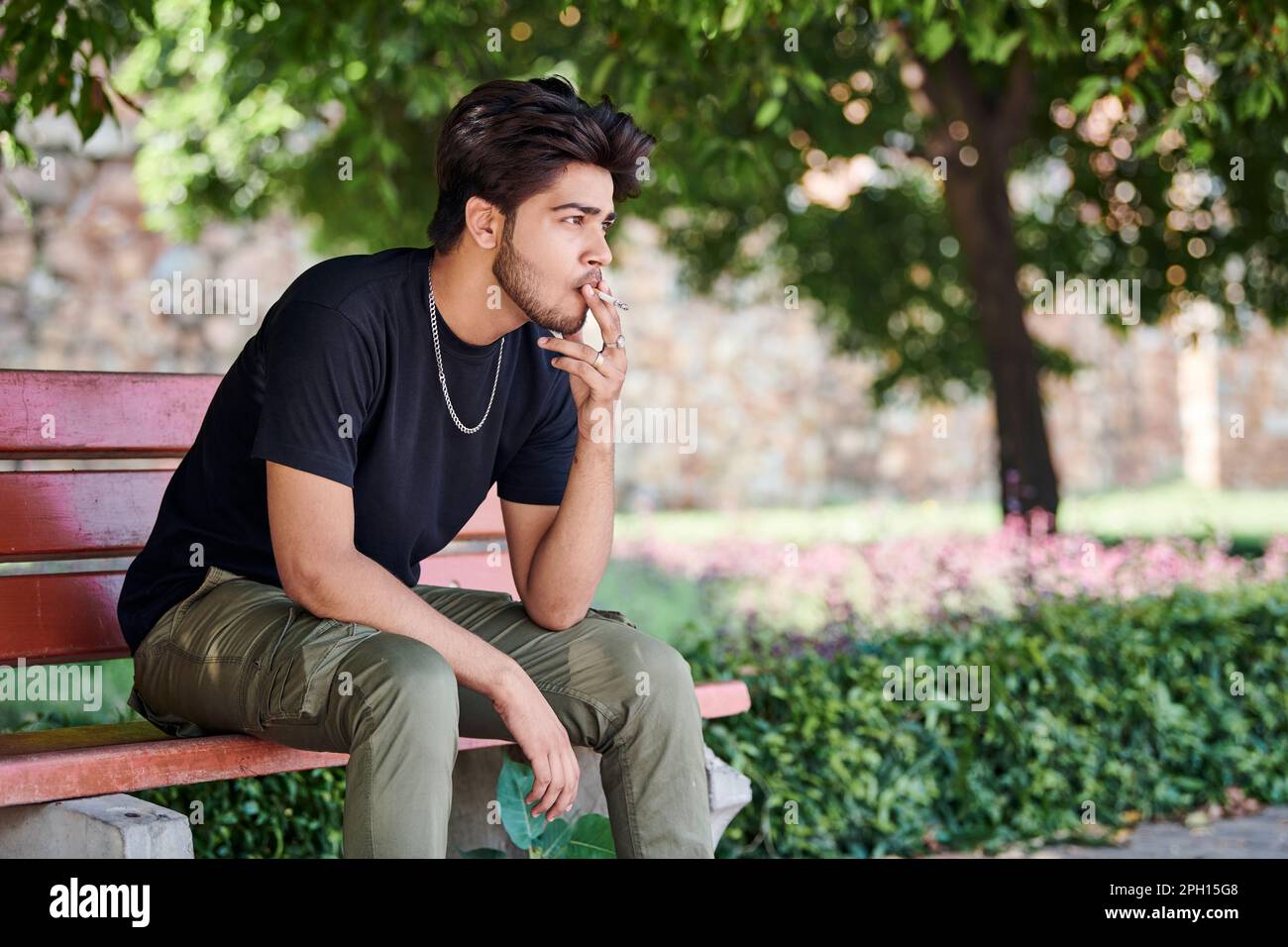 Young indian man smoker portrait in black t shirt and silver neck chain ...