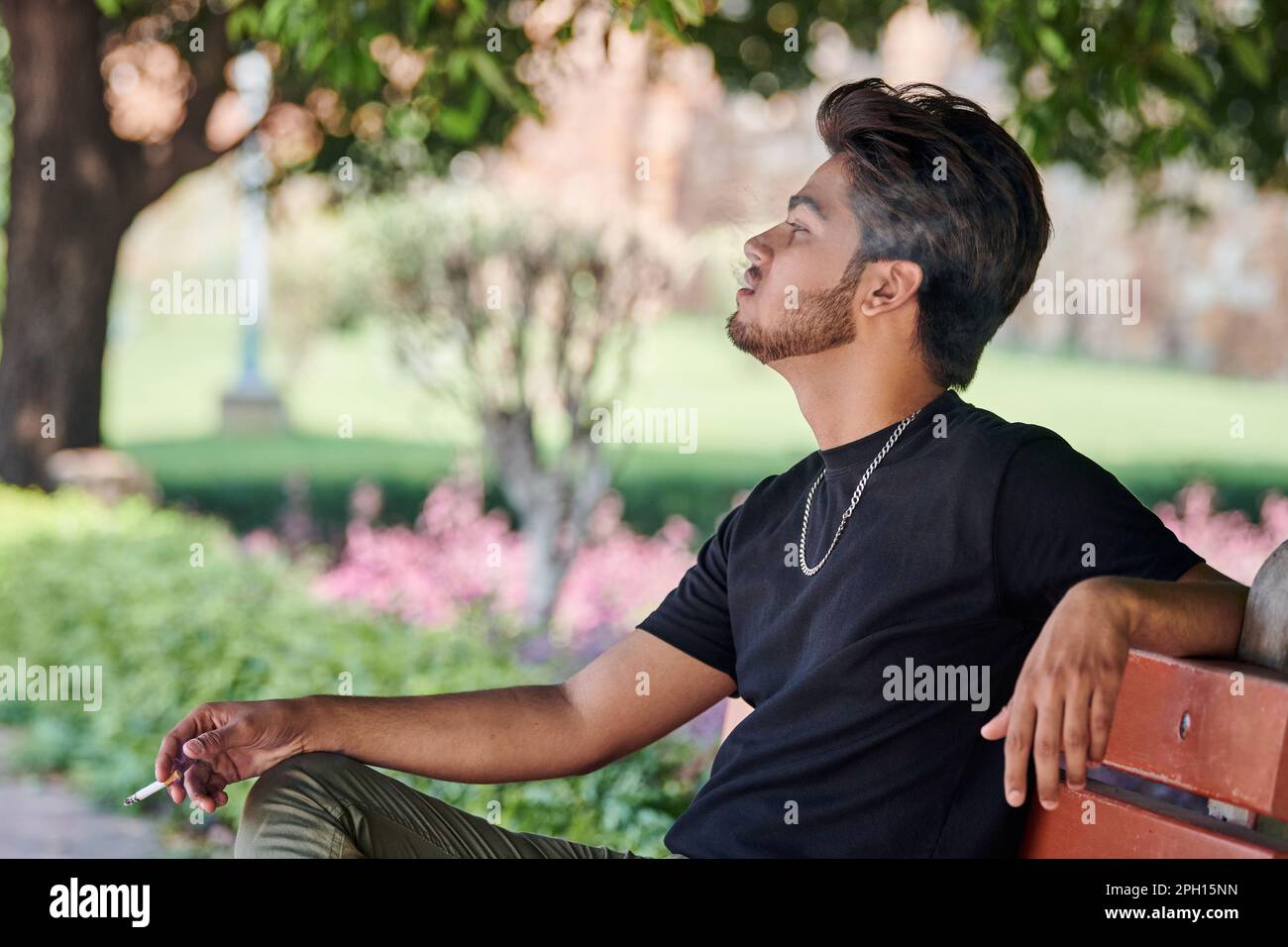 Attractive indian man smoker exhales cigarette smoke portrait in black ...