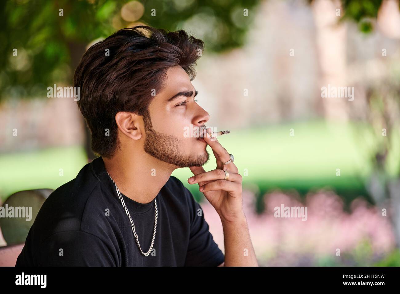 Young indian man smoker portrait in black t shirt and silver neck chain ...
