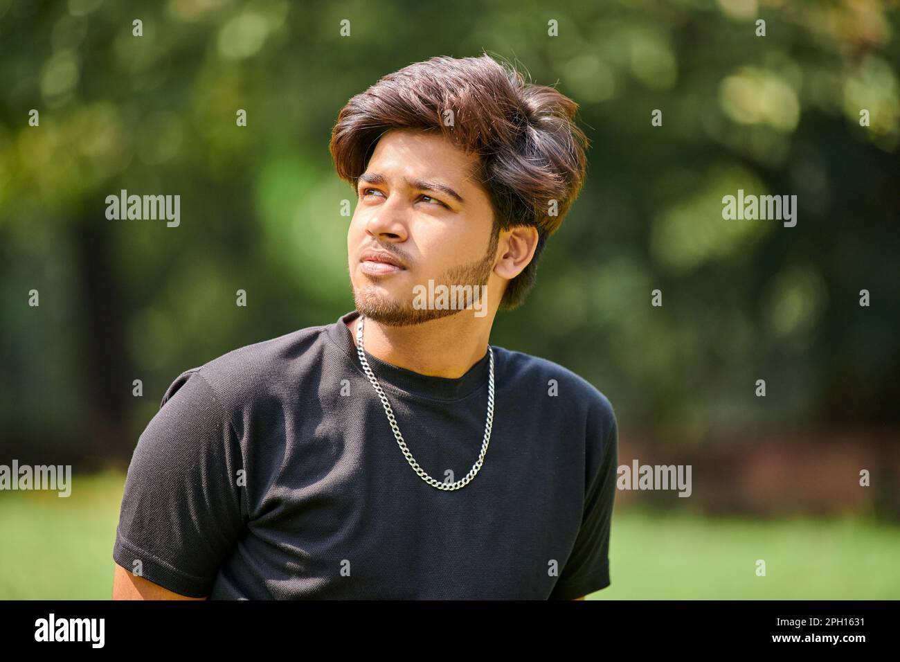 Attractive young indian man portrait in black t shirt and silver neck ...