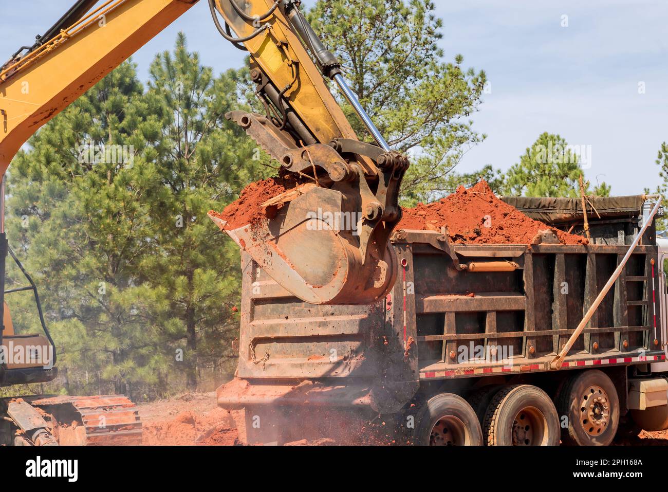 Excavator operator is carefully positioning scoop on soil is into ...