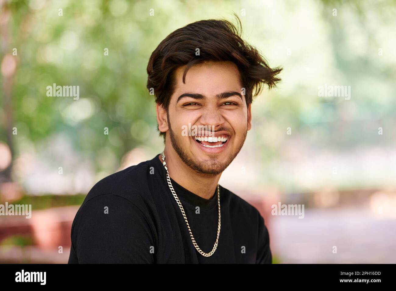Smiling young indian man candid portrait in black t shirt and silver ...