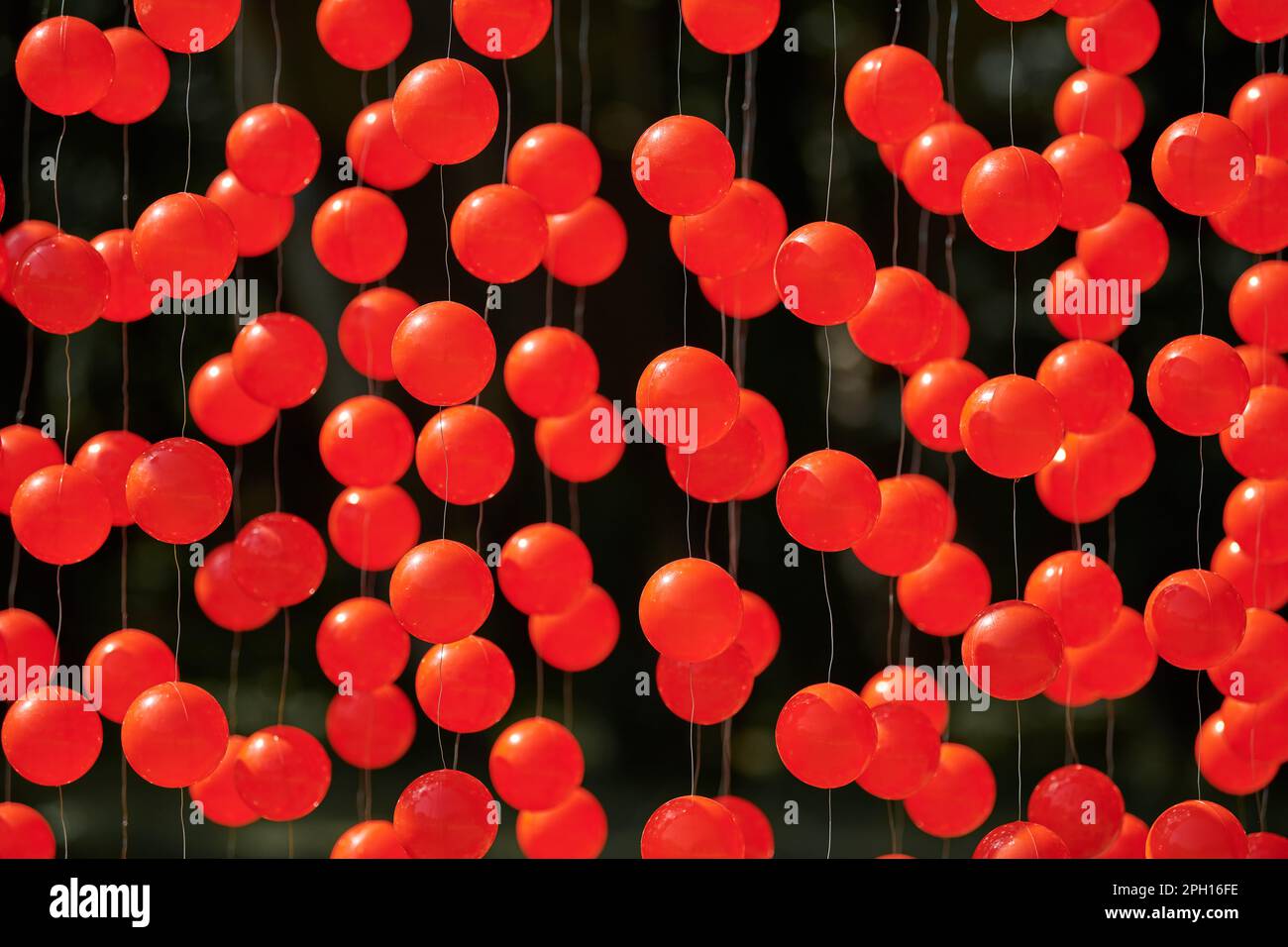 Red balls suspended on wire, outdoor art object symbolizing blood cells ...