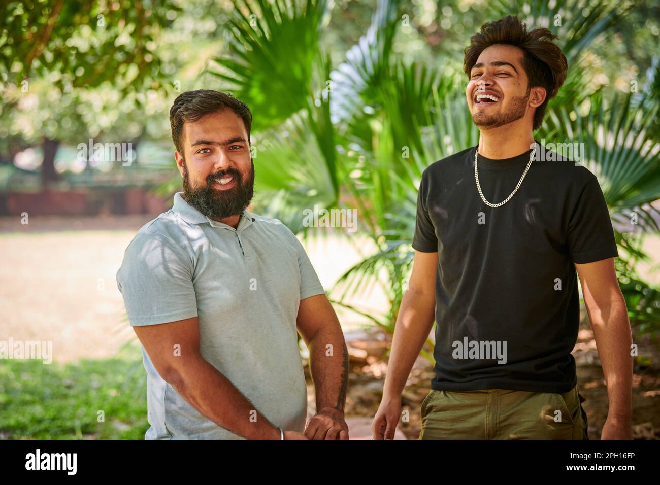 Two funny indian men laughing and speak Hindi in public park green palm ...