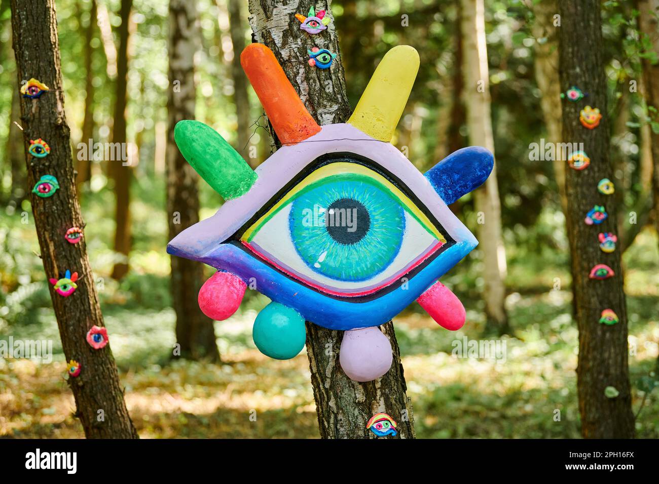 Art object of human eyes on tree trunk in green forest background ...