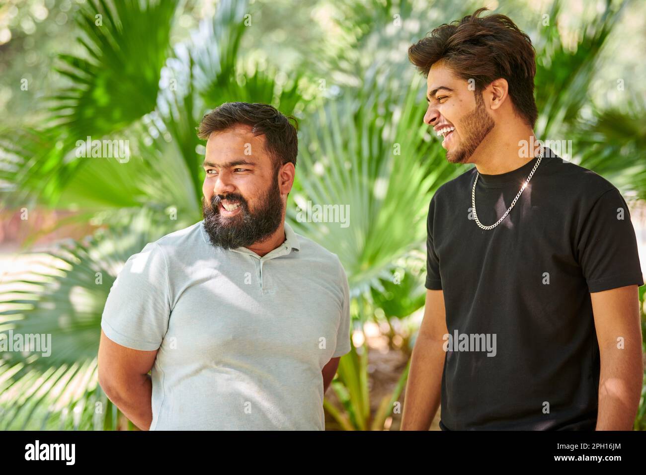 Two funny indian men laughing and speak Hindi in public park green palm ...