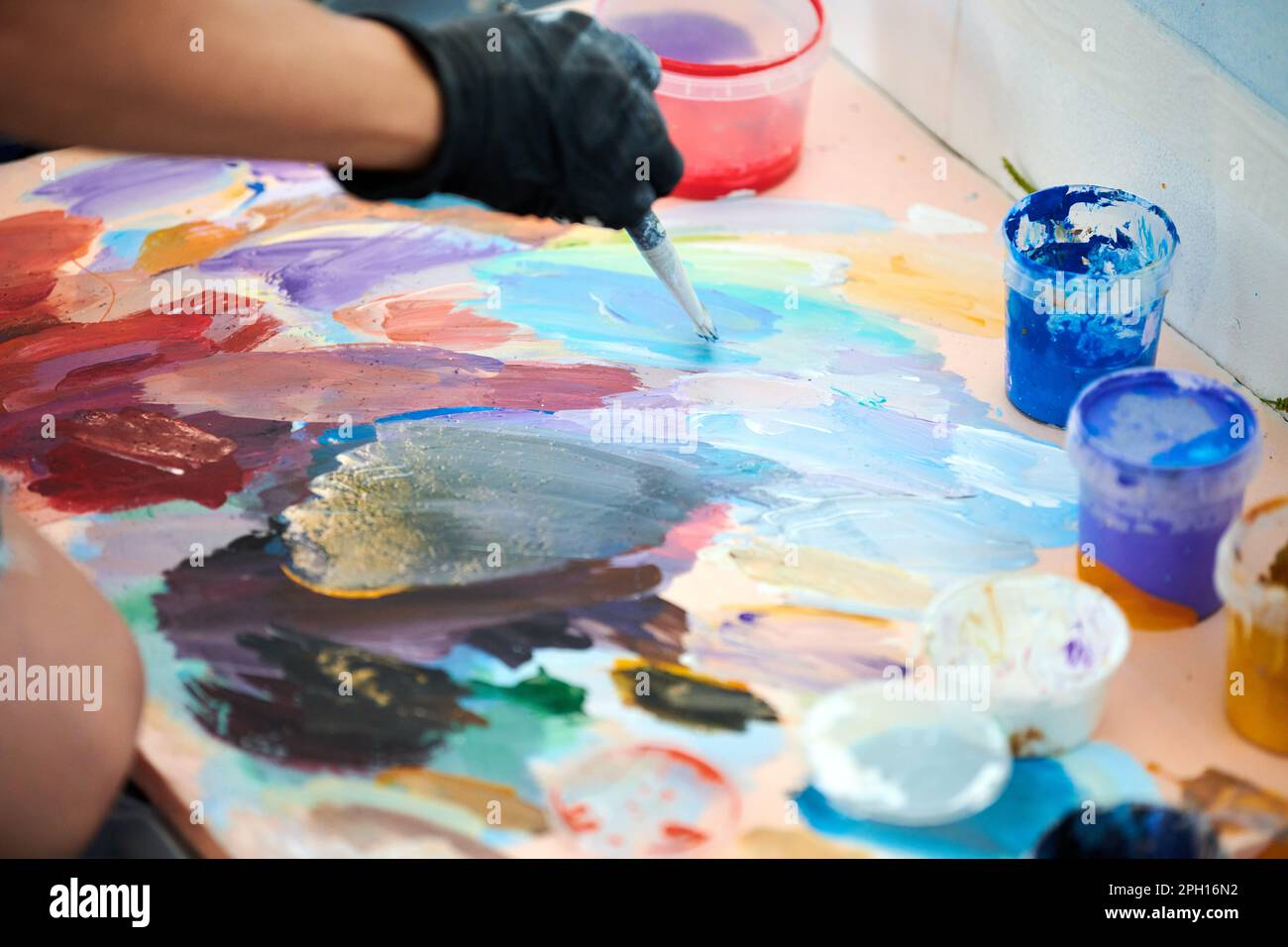 Artist hand in black gloves holds paint brush and choose color from ...