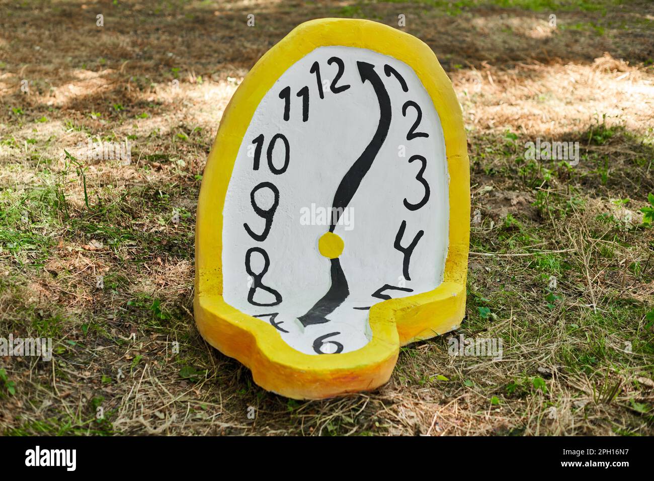 Melting clock art object lying on ground in forest at outdoor art ...