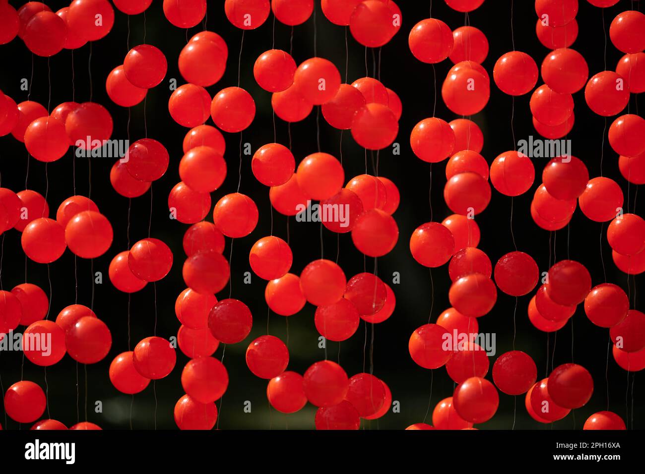 Red balls suspended on wire, outdoor art object symbolizing blood cells ...