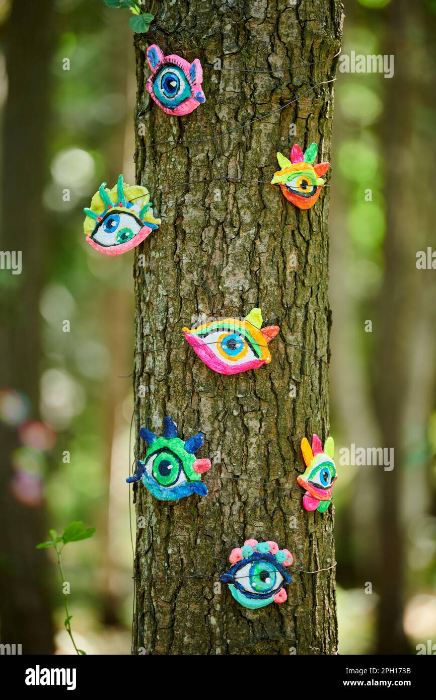 Art object of human eyes on tree trunk in green forest background ...