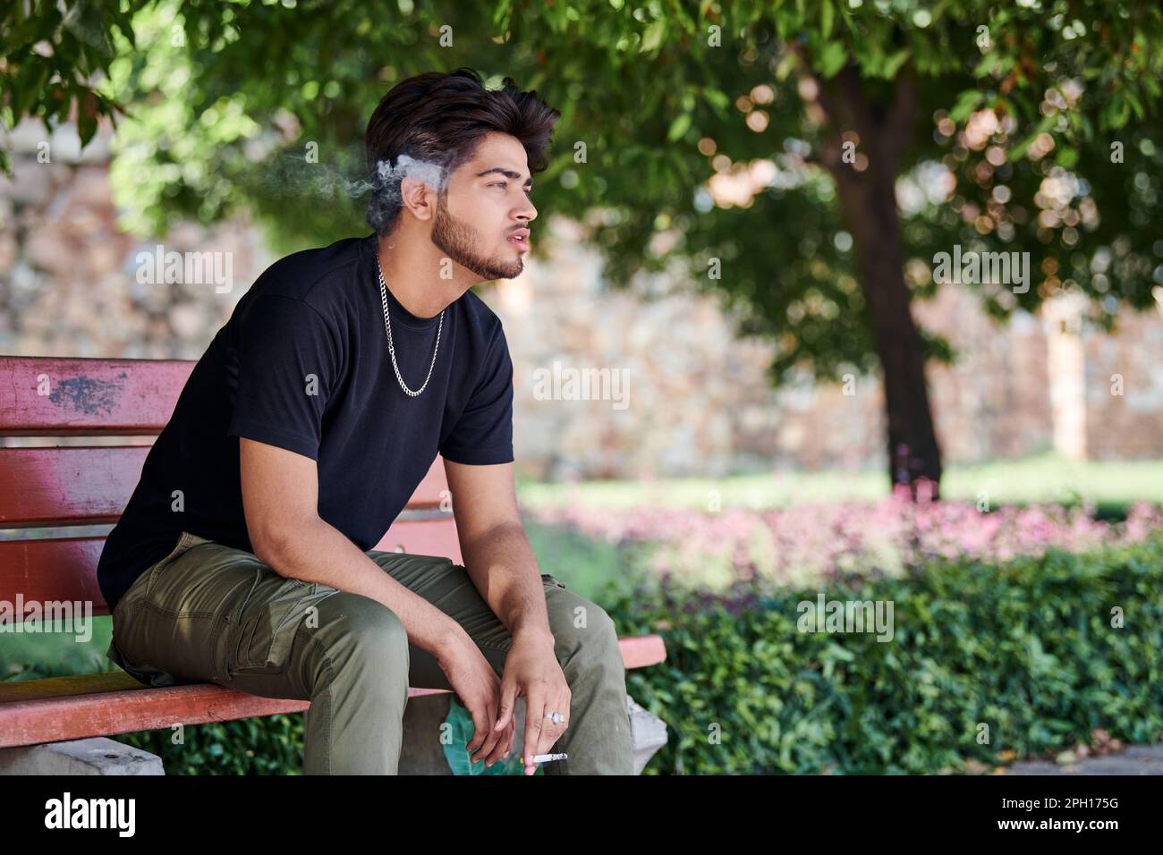 Attractive indian man smoker exhales cigarette smoke portrait in black ...