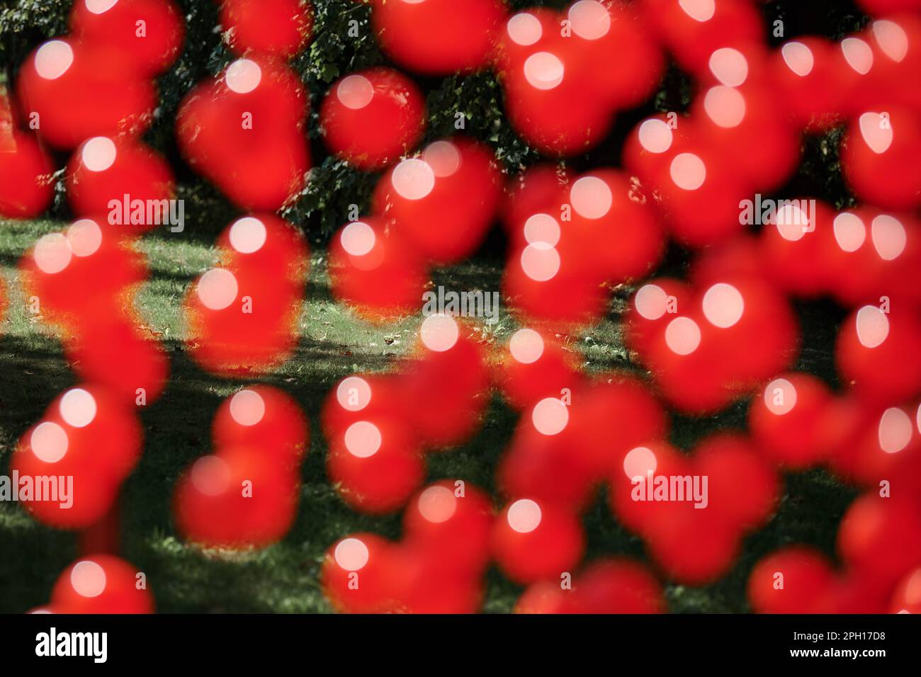 Blurred defocused red balls suspended on wire, outdoor art object ...