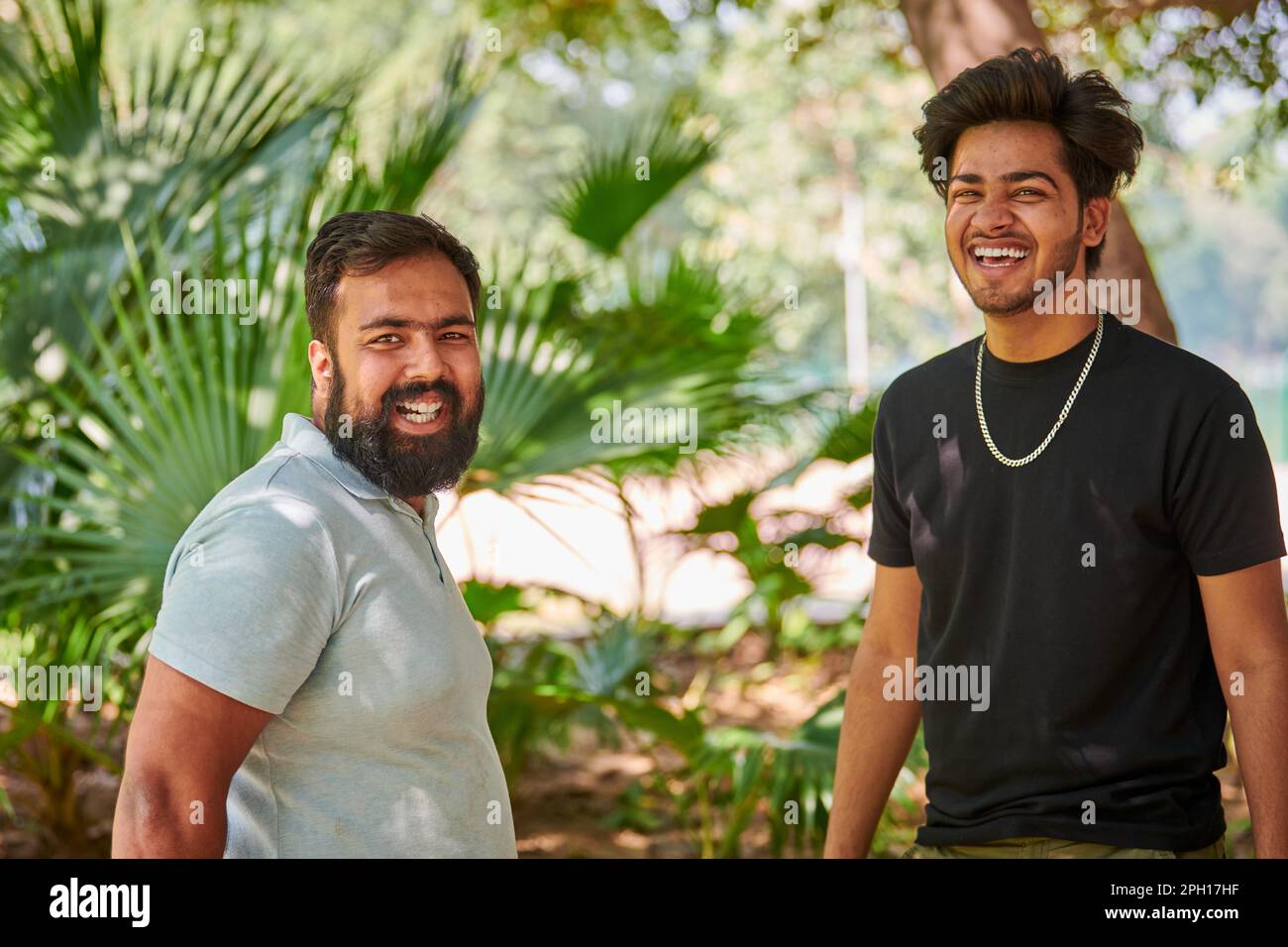 Two funny indian men laughing and speak Hindi in public park green palm ...