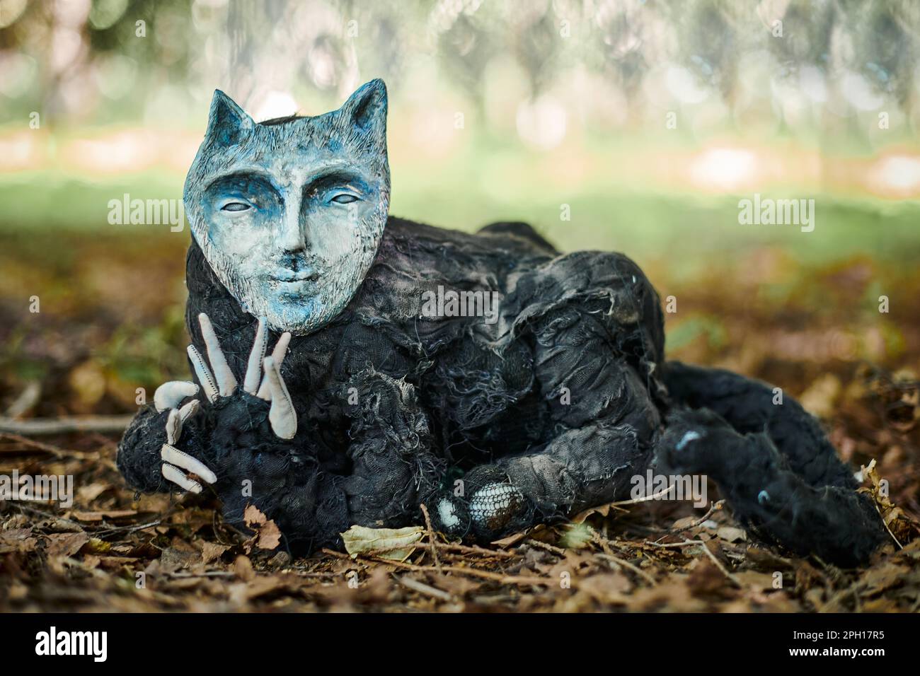 Black cat in human face mask art object at outdoor art exhibition in ...