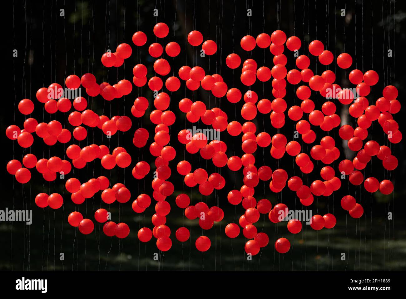 Red balls suspended on wire, outdoor art object symbolizing blood cells ...