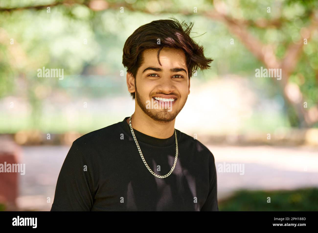 Smiling young indian man candid portrait in black t shirt and silver ...