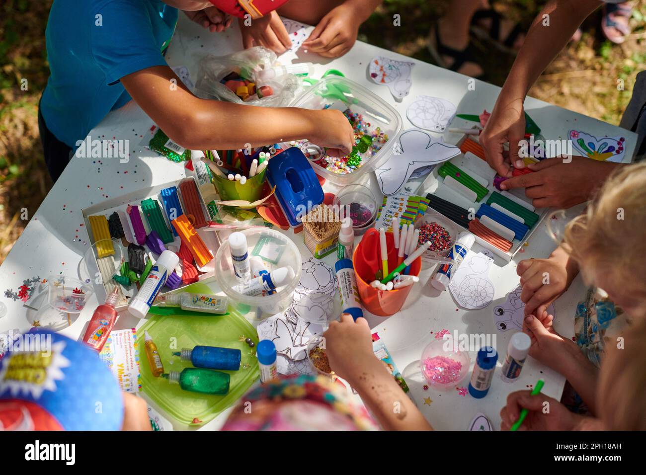 Children paper crafting with parents in outdoor children party ...