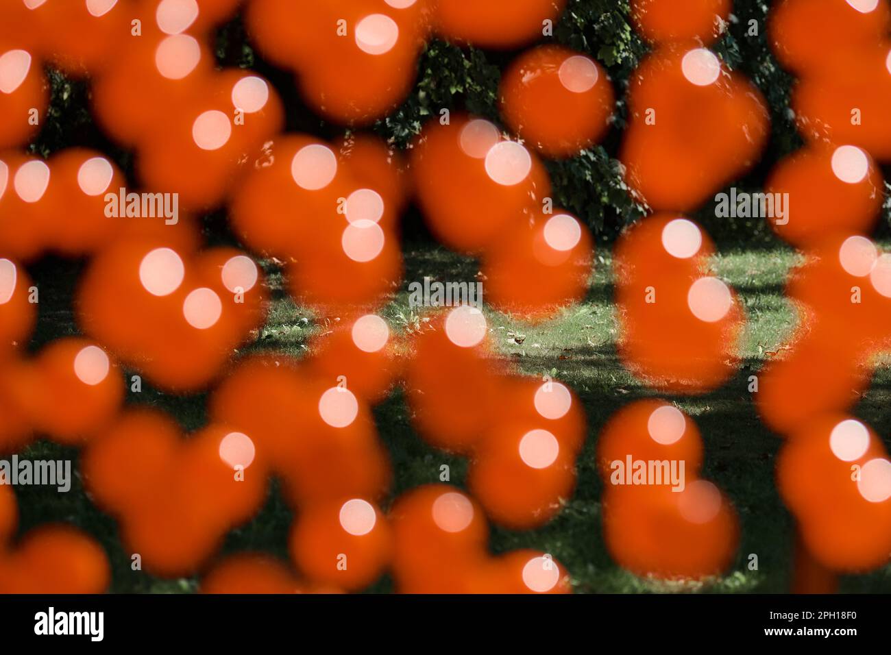 Blurred defocused orange balls suspended on wire, outdoor art object ...