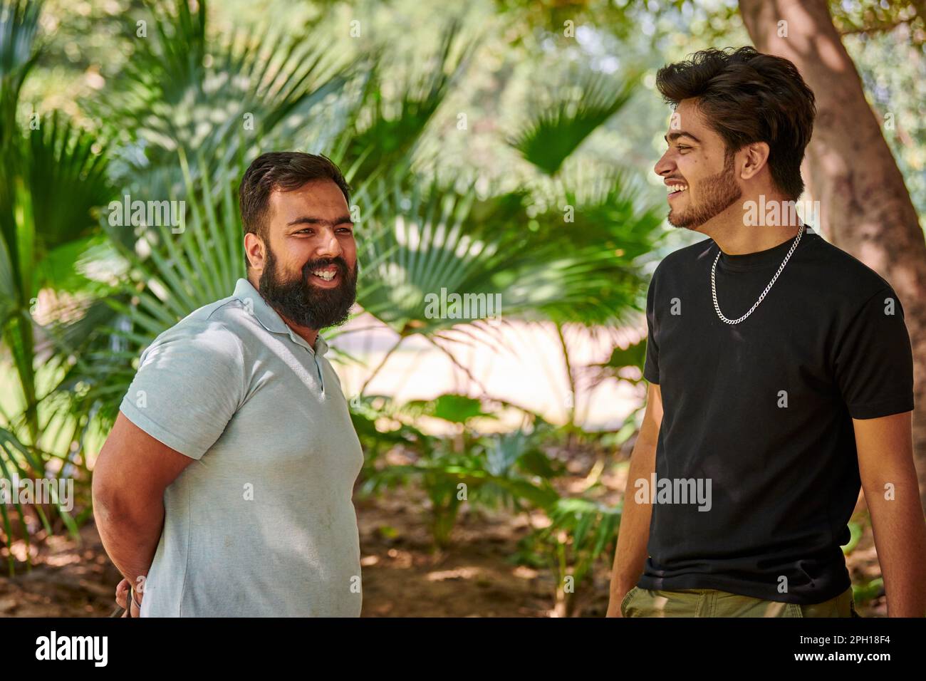 Two funny indian men laughing and speak Hindi in public park green palm ...