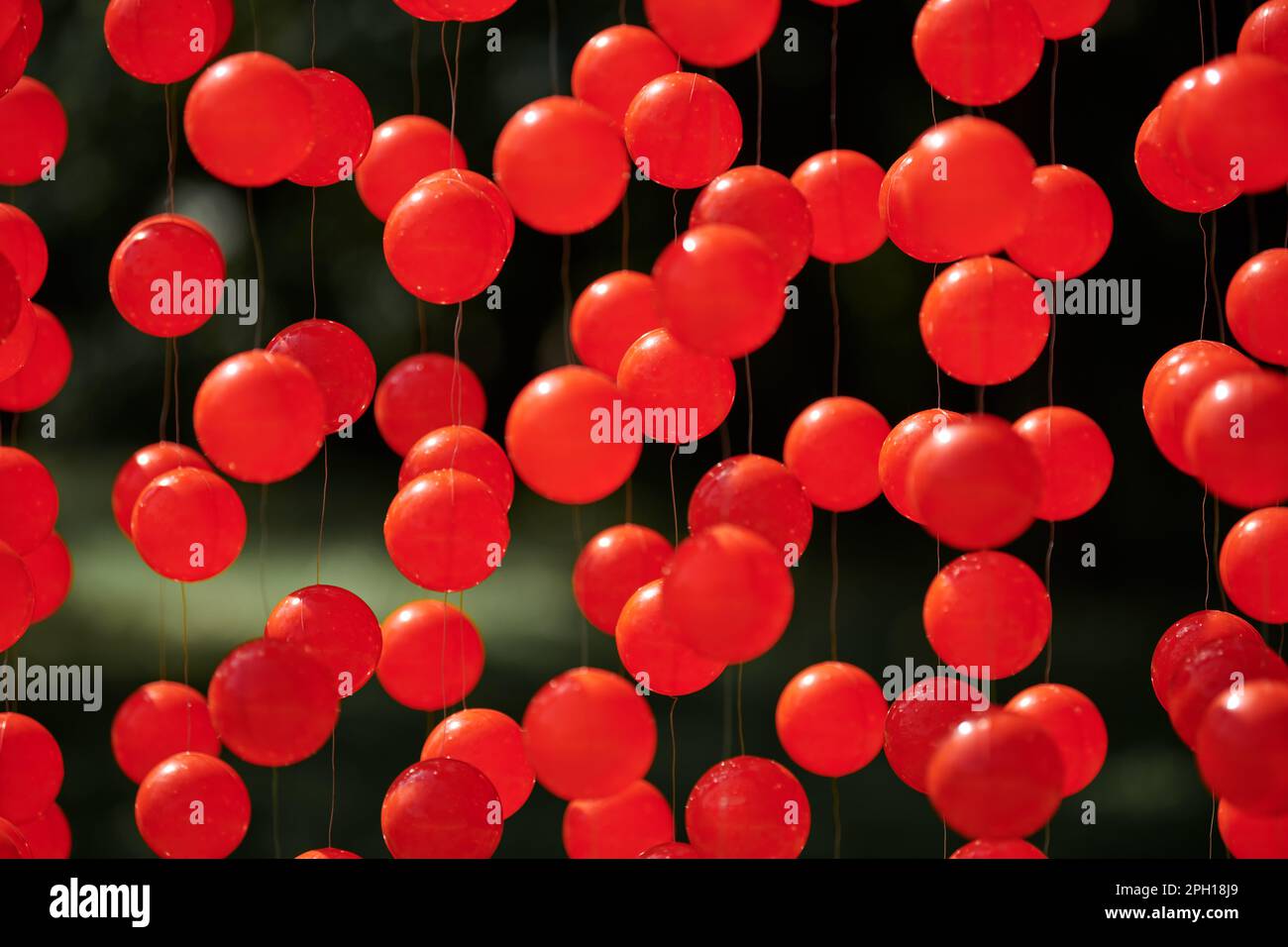 Red balls suspended on wire, outdoor art object symbolizing blood cells ...