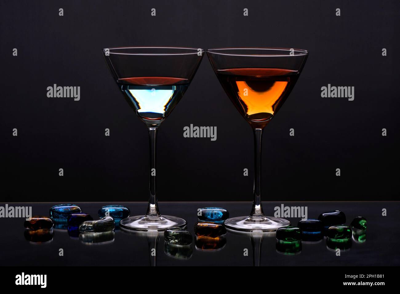 two glasses of different alcoholic cocktails on a black background ...