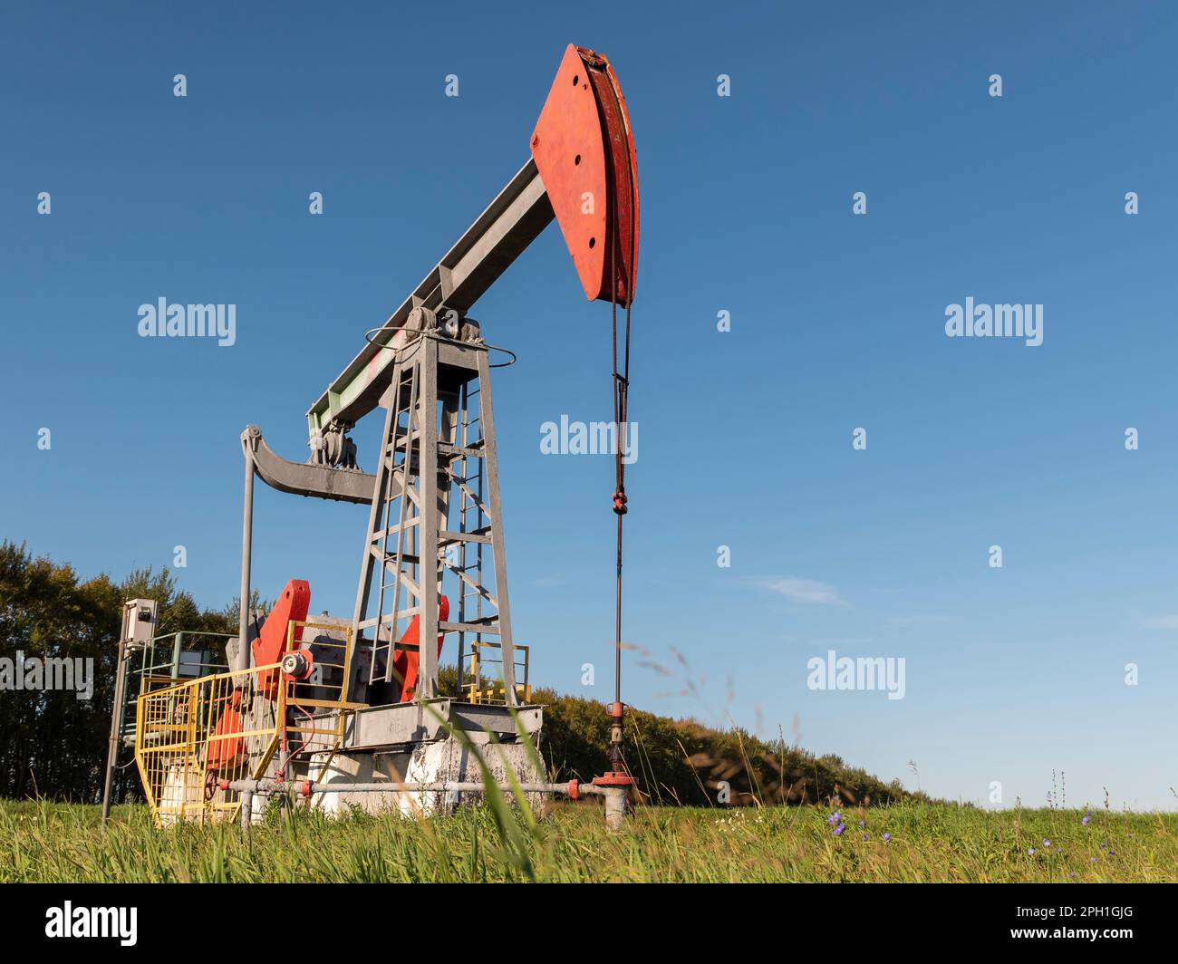 Operating oil and gas well in oil field, profiled against the blue sky ...