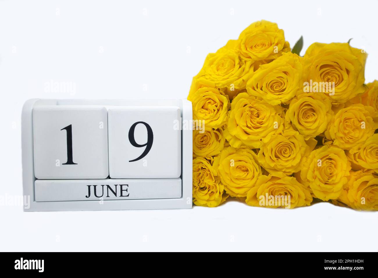 Wooden, white calendar June 19, bouquet of yellow roses lie next to it ...