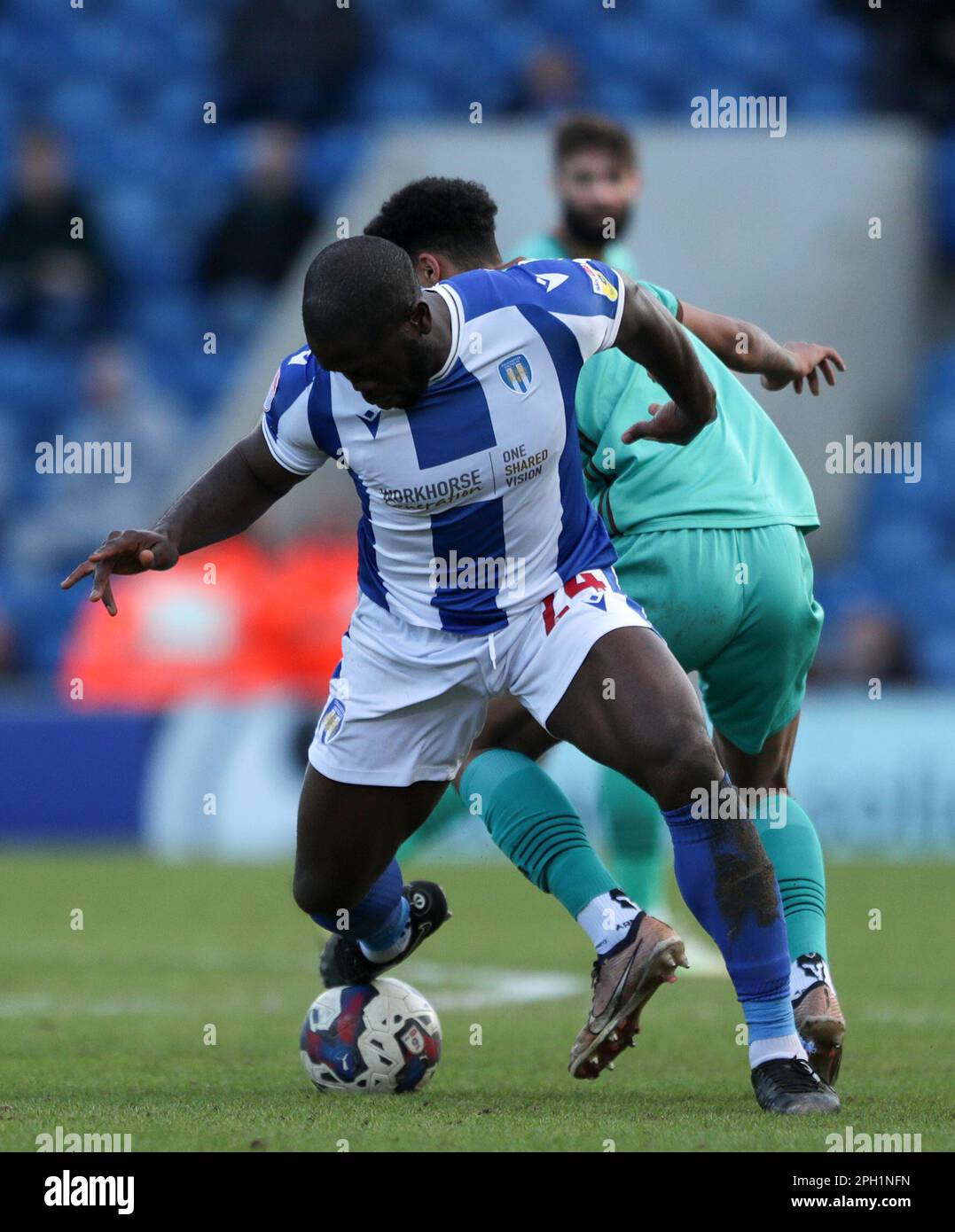 John Akinde of Colchester United is tackled by Ethan Bristow of ...