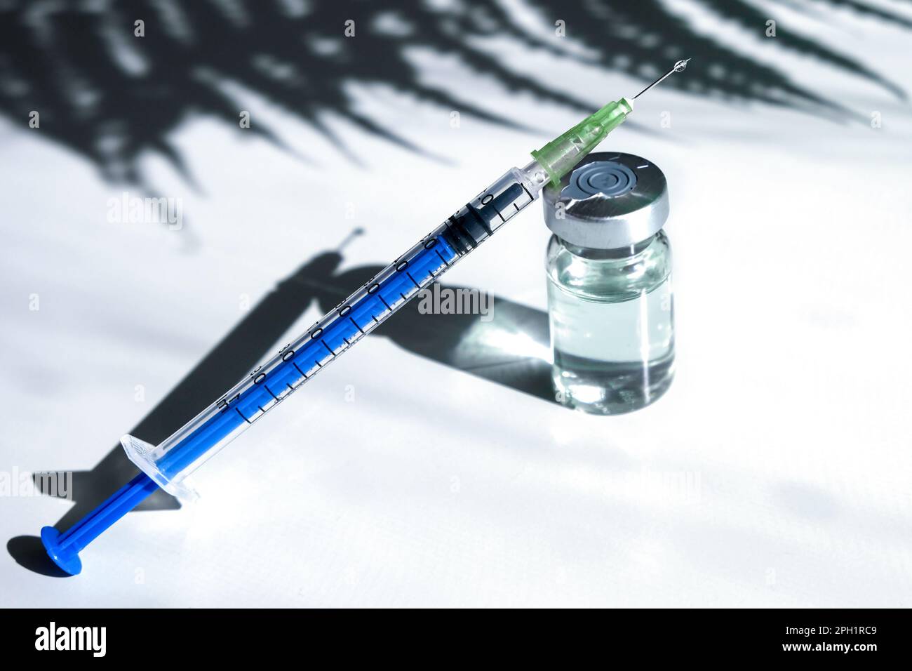 A glass ampoule with a clear liquid with a syringe. Syringe next to the ...