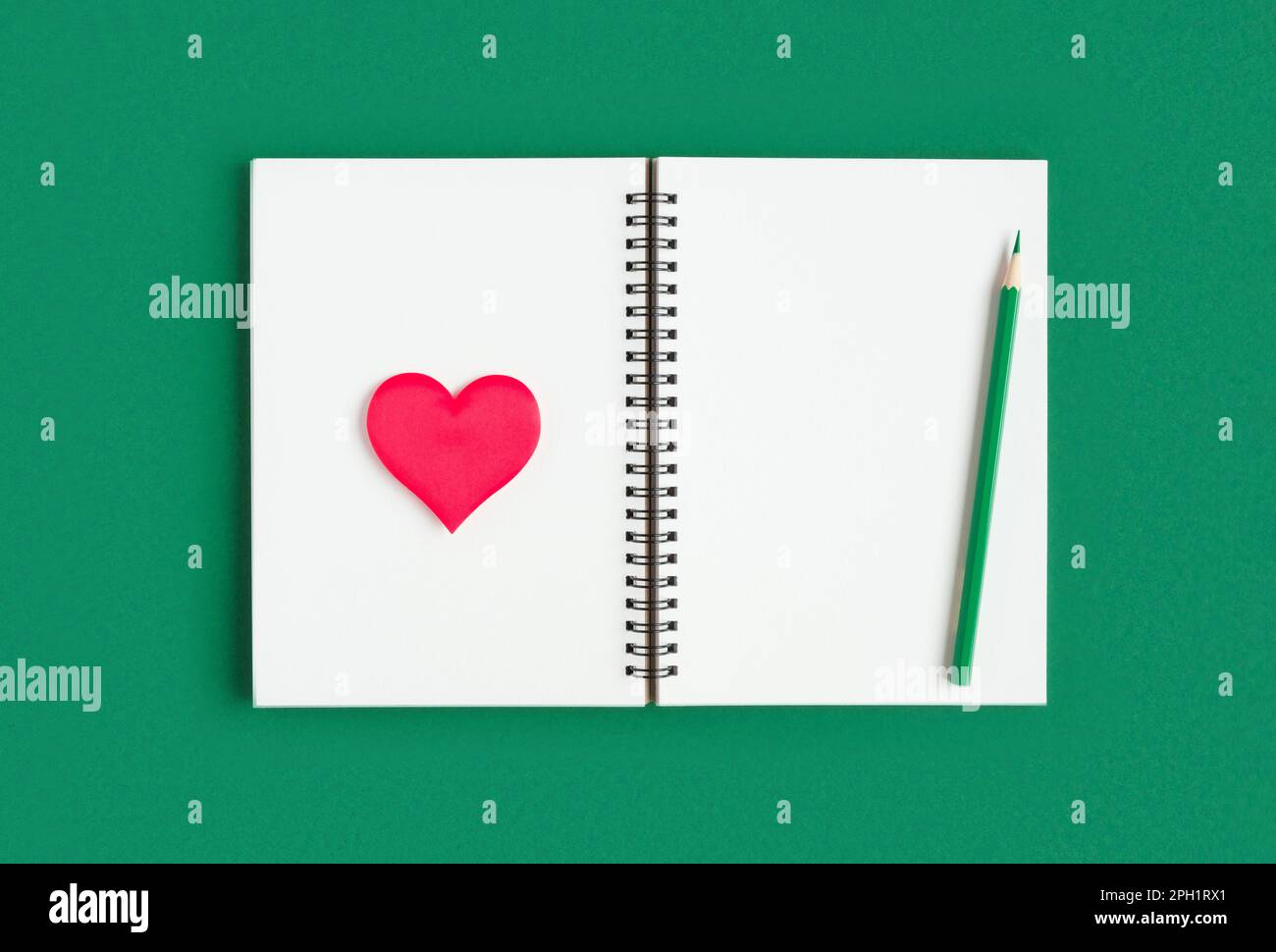 Notebook with pencil, red heart. Open notebook on green emerald color ...