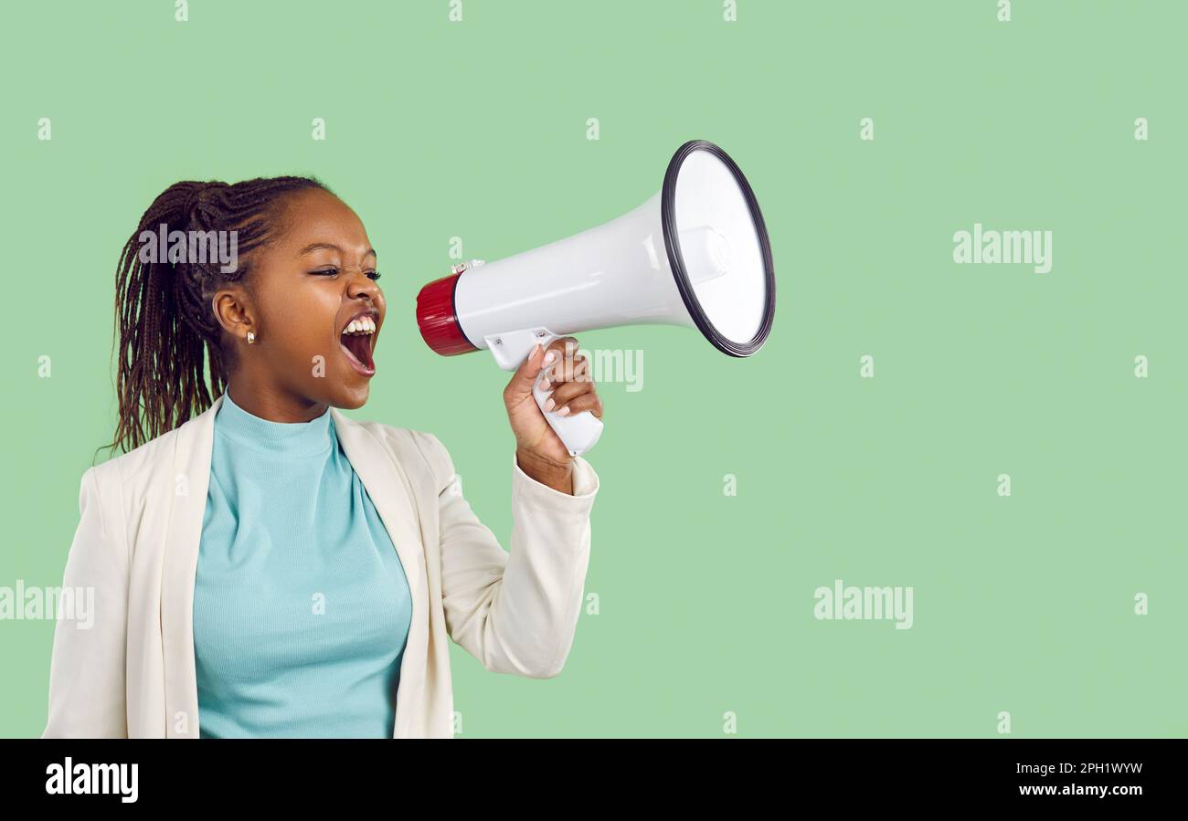 Young woman with megaphone in her hand shouting advertising something ...