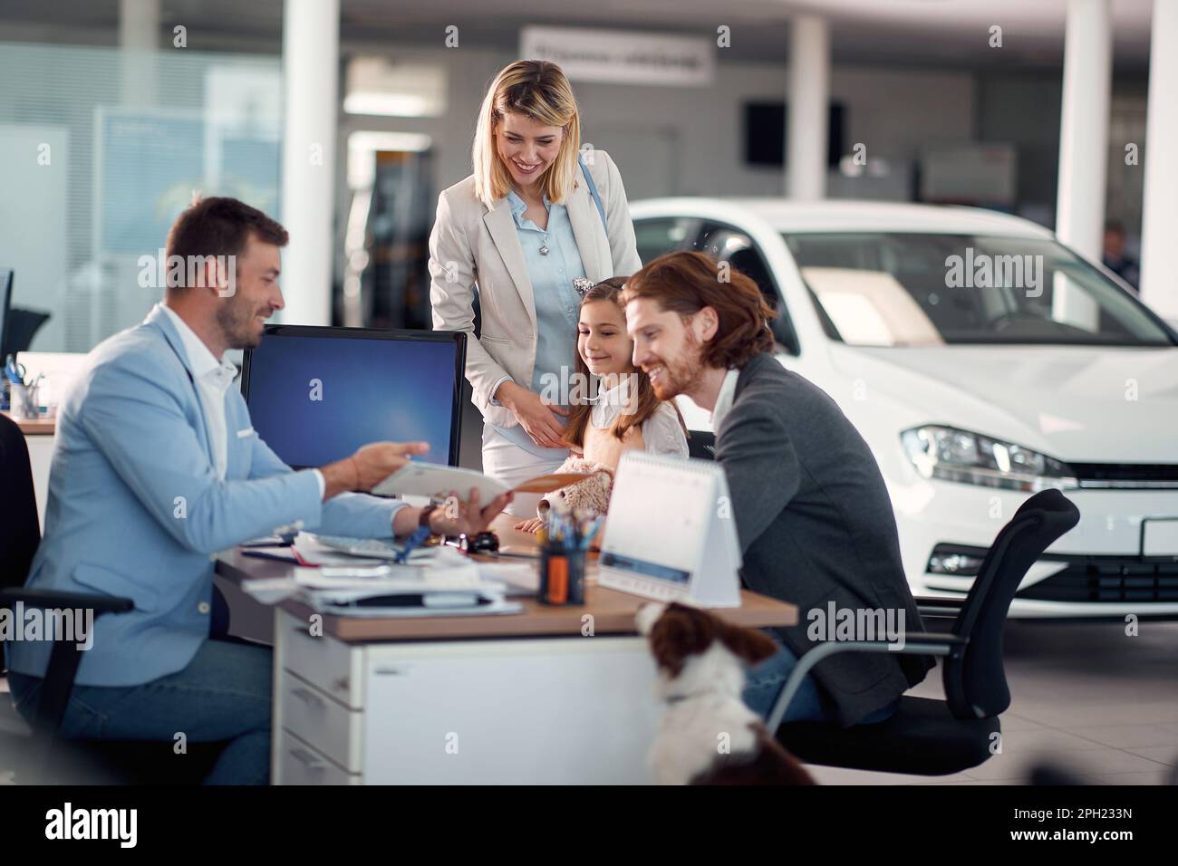 Young happy family with salesman in car selling salon Stock Photo - Alamy