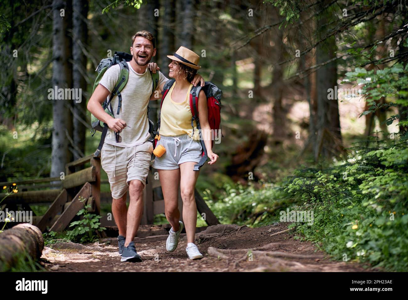 A young happy couple is walking the forest path on the mountain on a ...